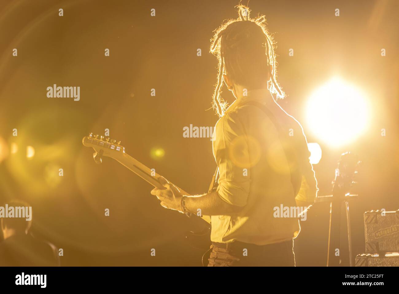 A guitarist seen from behind, playing in a foggy, atmospheric night ...