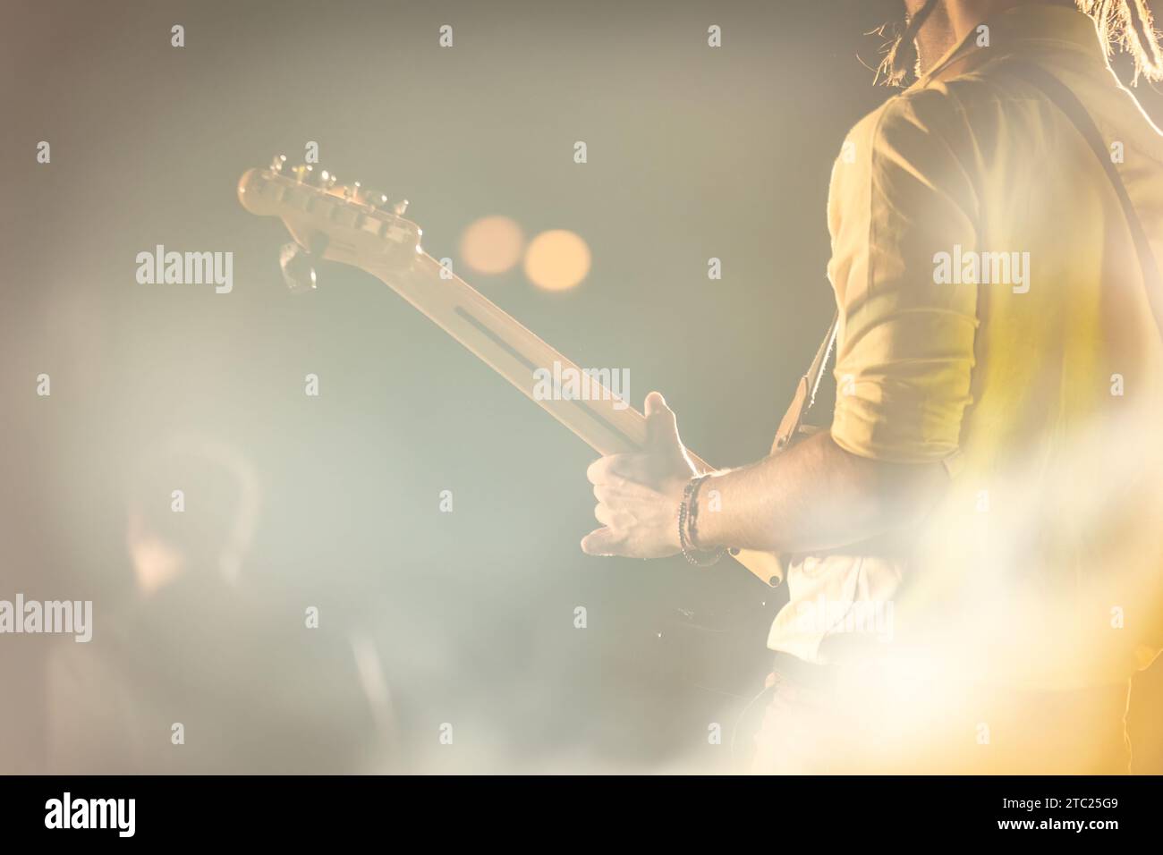 A guitarist seen from behind, playing in a foggy, atmospheric night ...