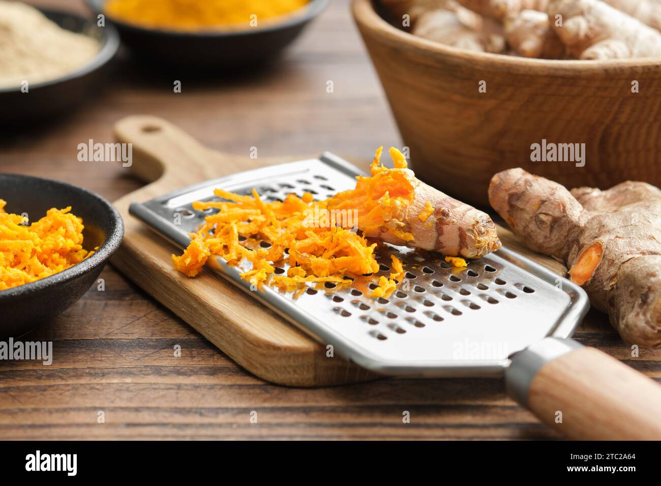 Grated fresh turmeric roots and grater. Bowls of whole and grated ...
