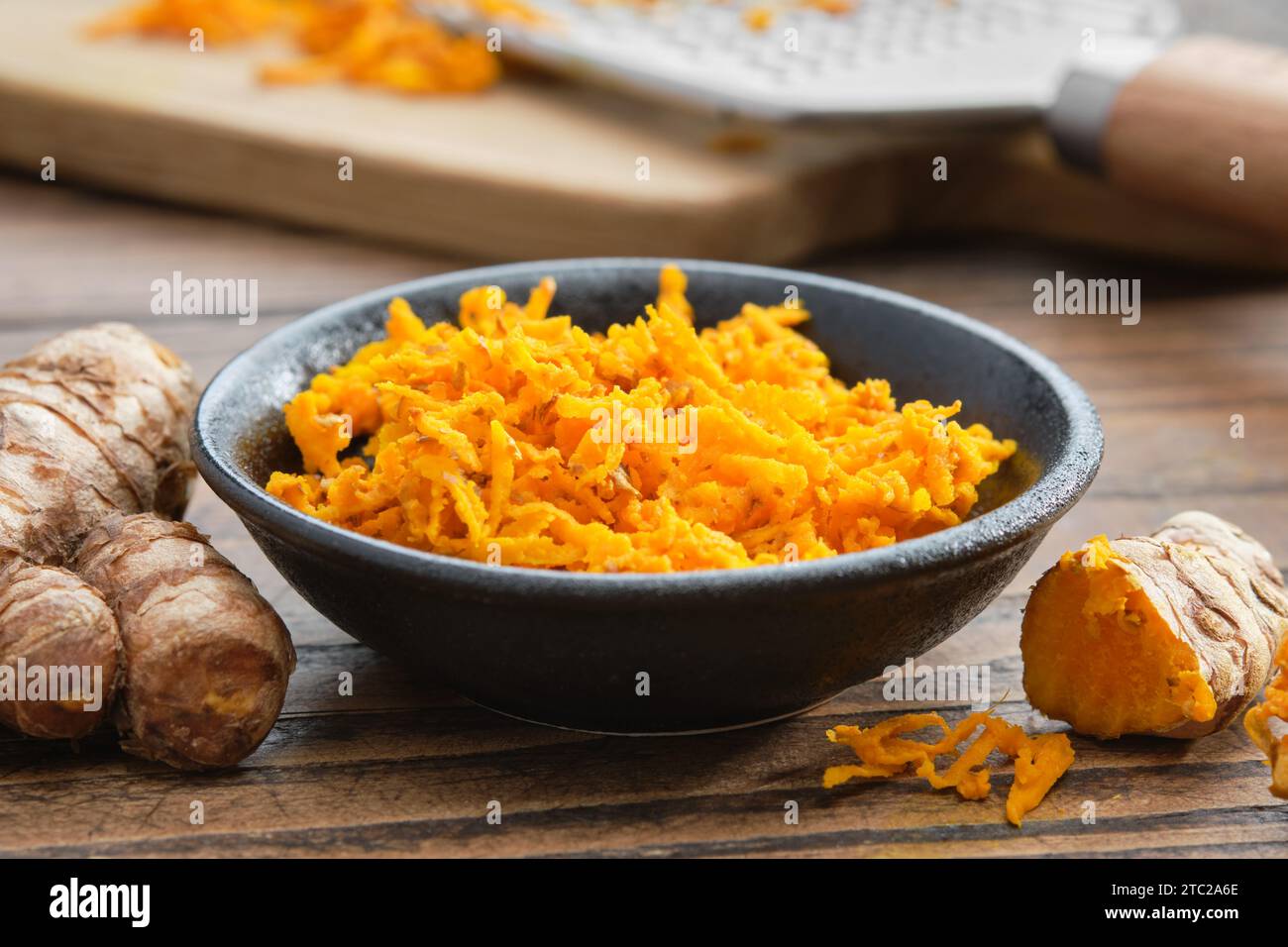 A bowl of grated fresh turmeric roots. Whole curcuma roots, cutting ...
