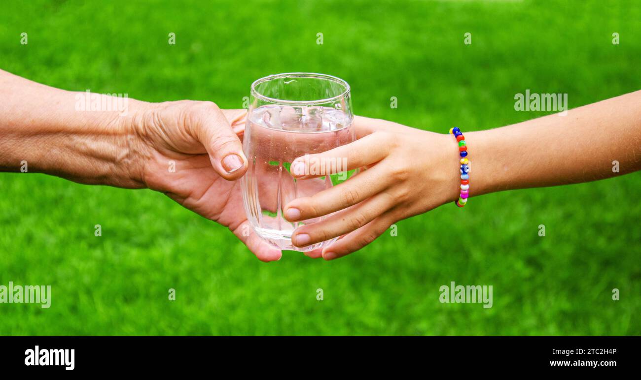 Grandmother giving a glass of clean water to a child. Selective focus ...