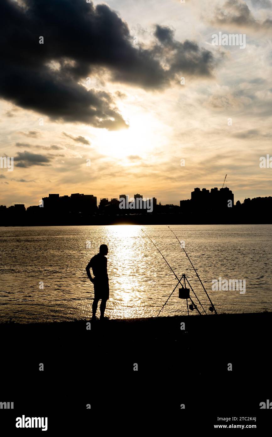 Silhouette of a man, fishing at Han River with the sunsets and view of ...