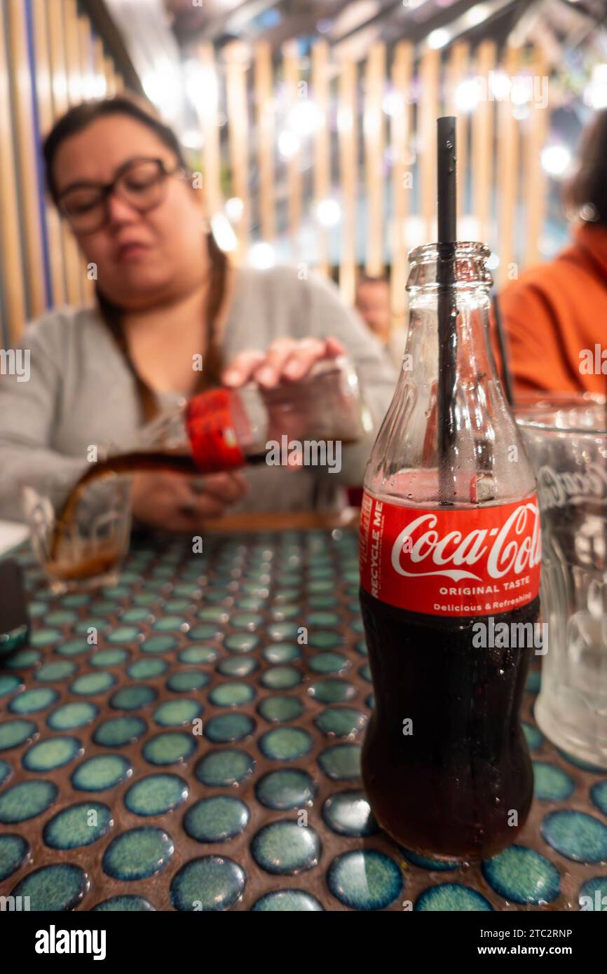 A bottle of original Coca-Cola with a straw in it on a table in a ...