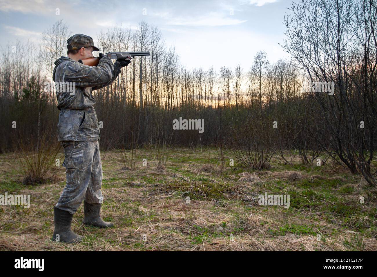 a hunter takes aim at a low-flying target in the evening against a ...