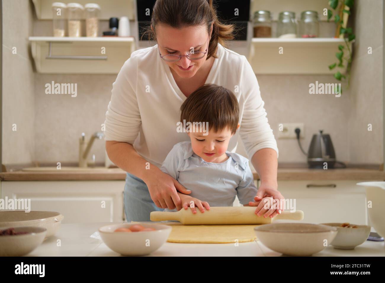 Cute baby boy and his mother making pie in the kitchen. Process of ...