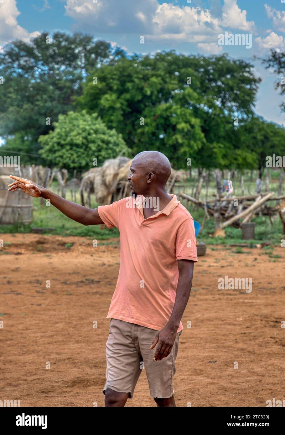village african young man, standing in the yard , showing directions ...