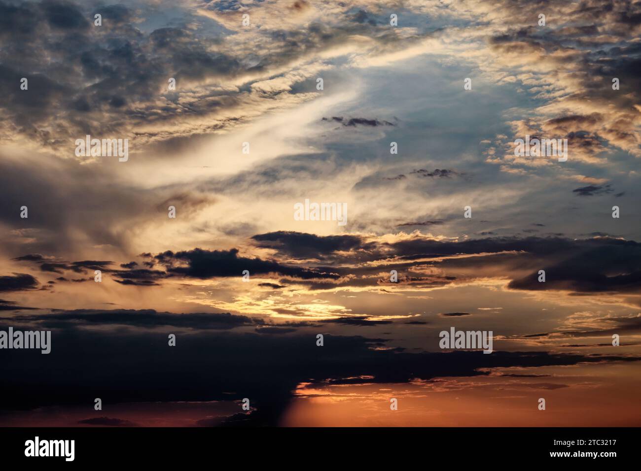 The sun shining through scattered clouds at sunset Stock Photo - Alamy