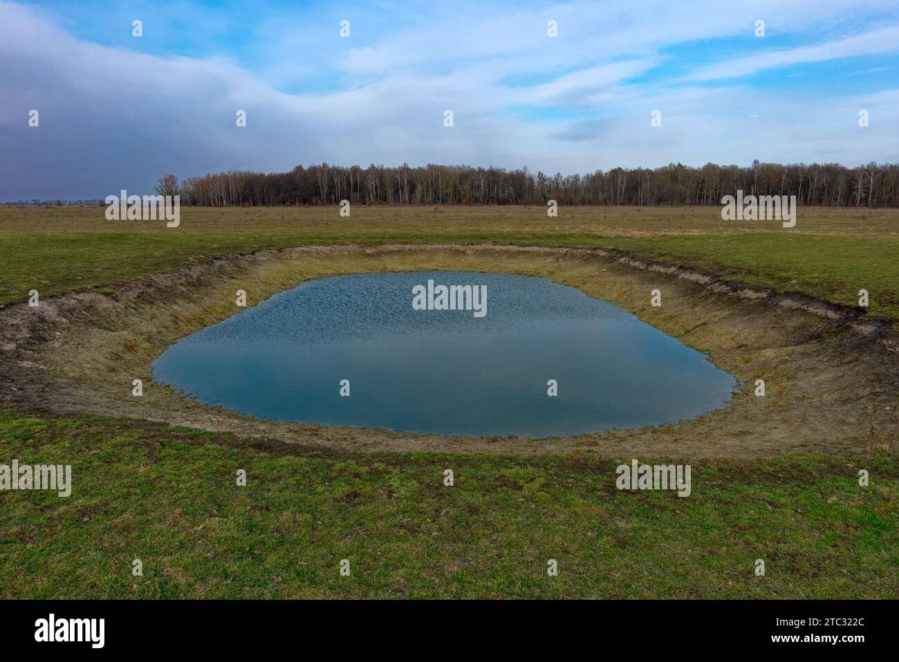 The image showcases a small body of water nestled in a field ...