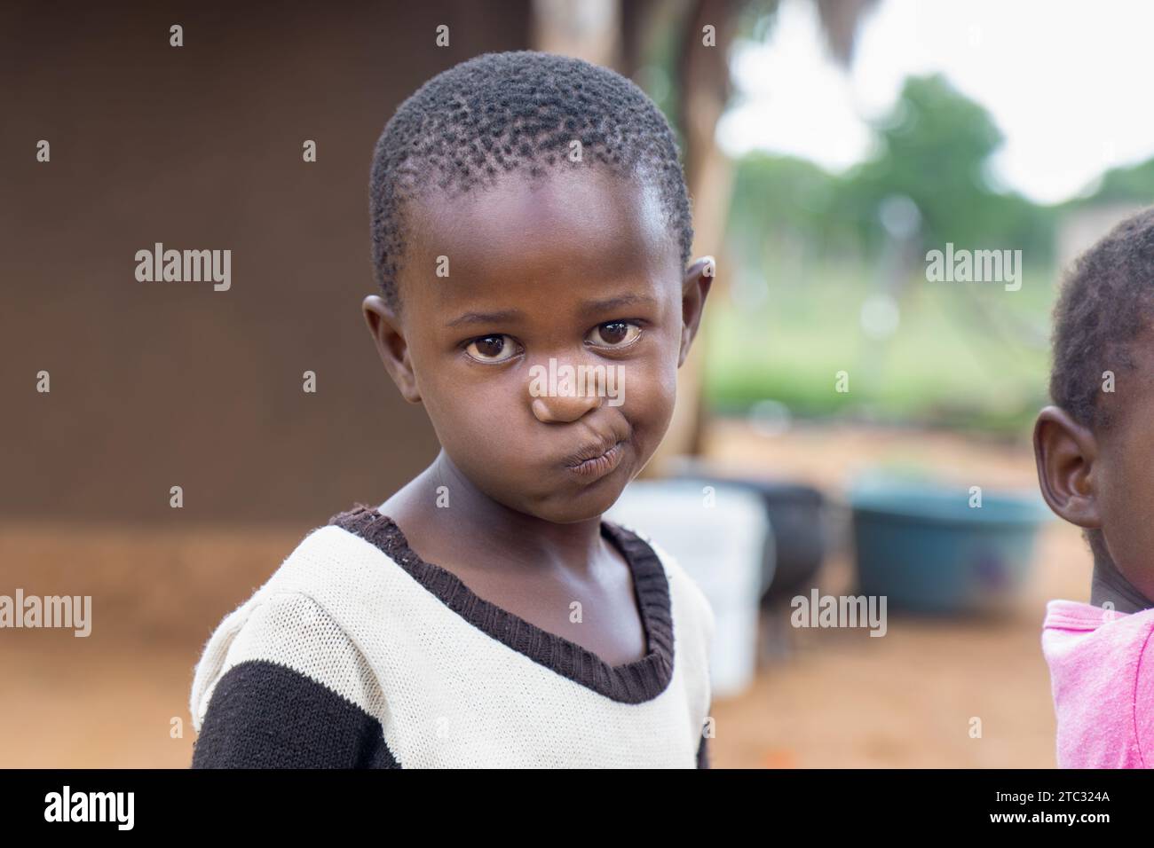 village african child, standing in the yard , playing pulling faces ...