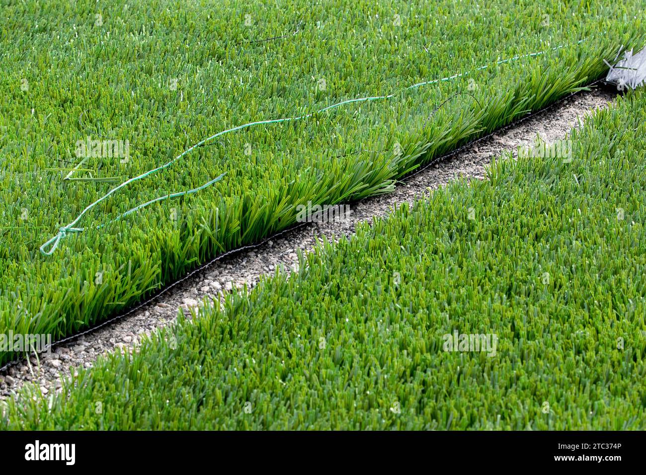 Closeup installation of football field with artificial turf with grass ...