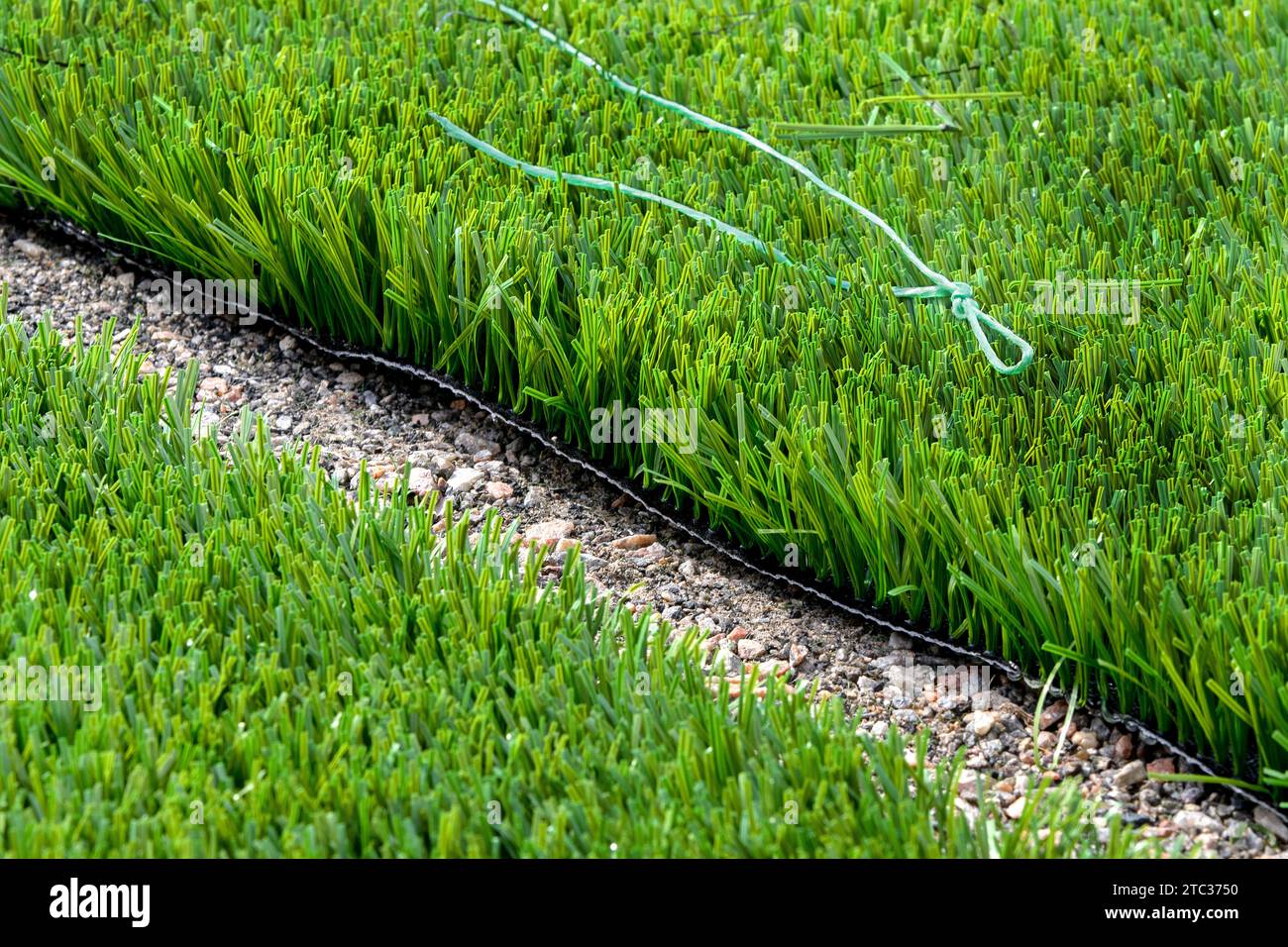 Closeup installation of football field with artificial turf with grass ...