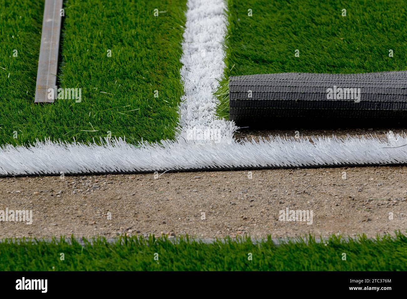 Closeup installation of football field with artificial turf with grass ...