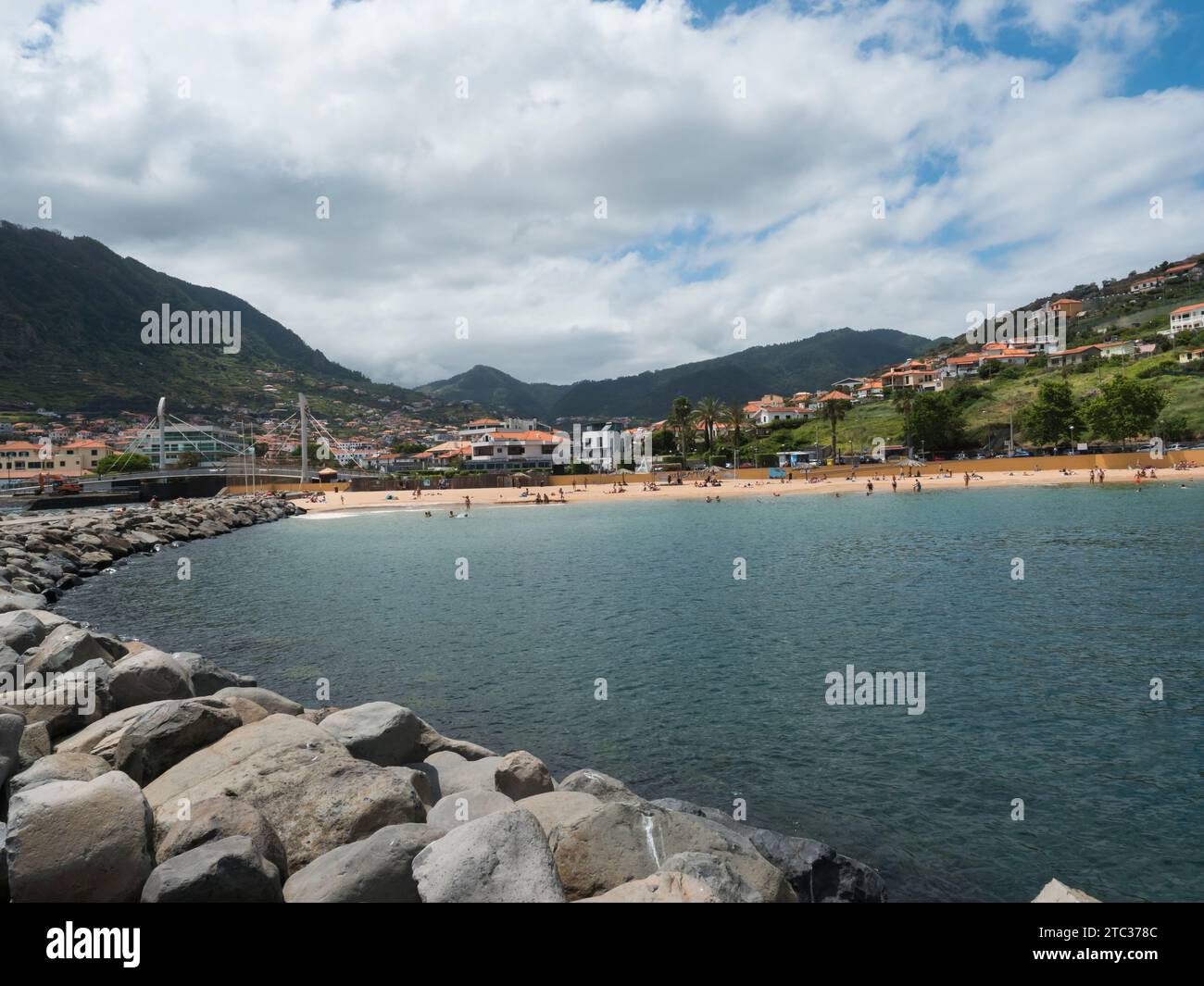 View of Machico bay with golden sand beach, palm trees and houses ...