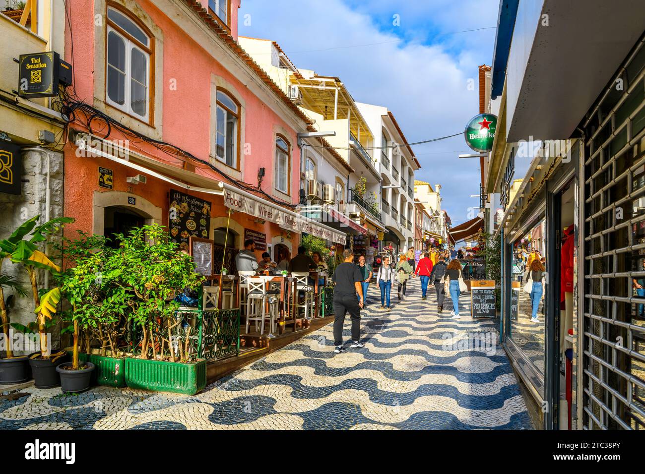 A busy street of shops and sidewalk cafes with traditional Calcada ...