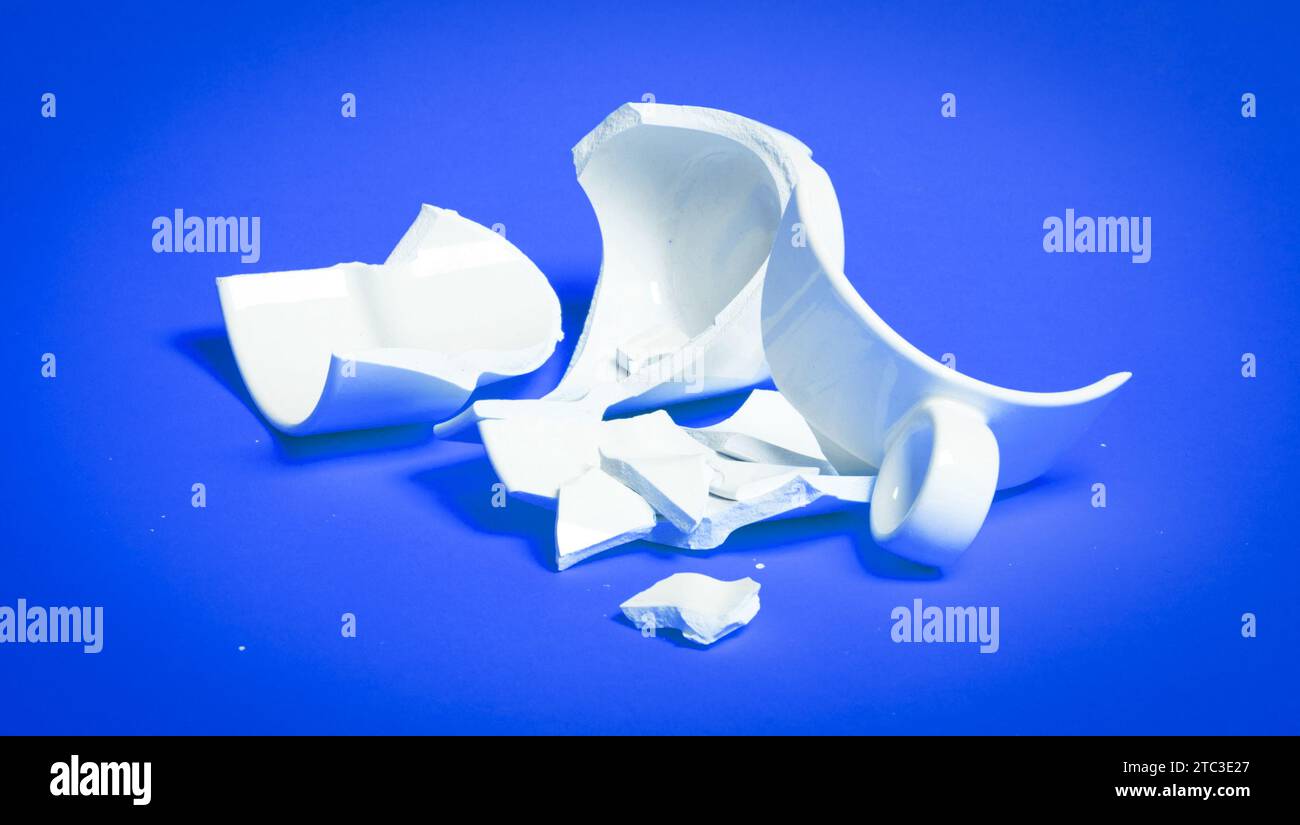 Broken cup isolated on a solid blue background Stock Photo - Alamy
