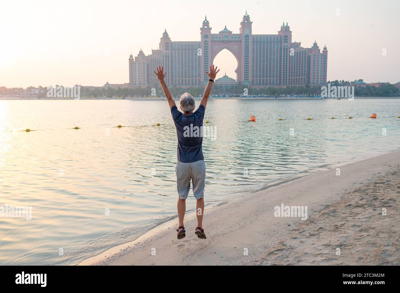 Senior caucasian man jumping high at Palm Jumeirah in Dubai, captured ...