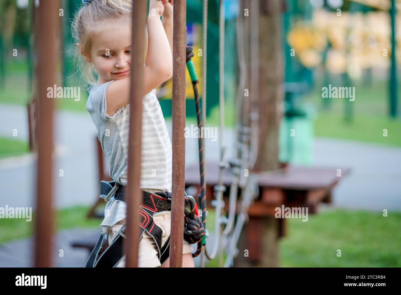 Cute girl enjoying activity in a climbing adventure park. Girl goes on ...