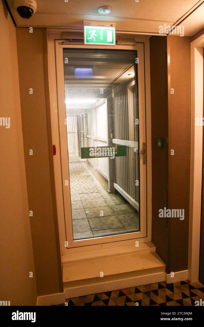 Emergency exit, glass door towards outside corridor, with exit sign ...