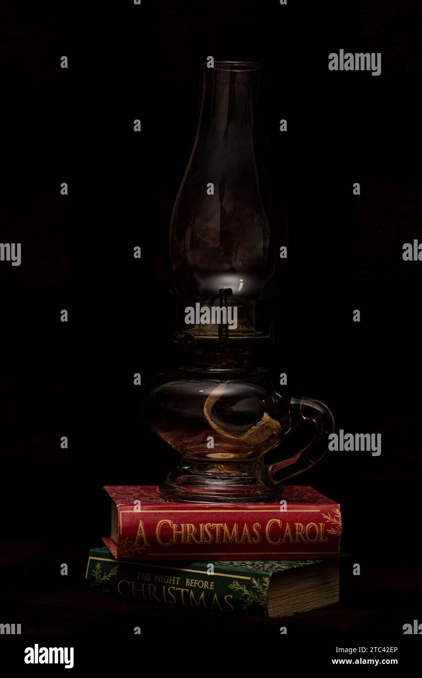 A still life composition of a candle and books illuminated by the ...