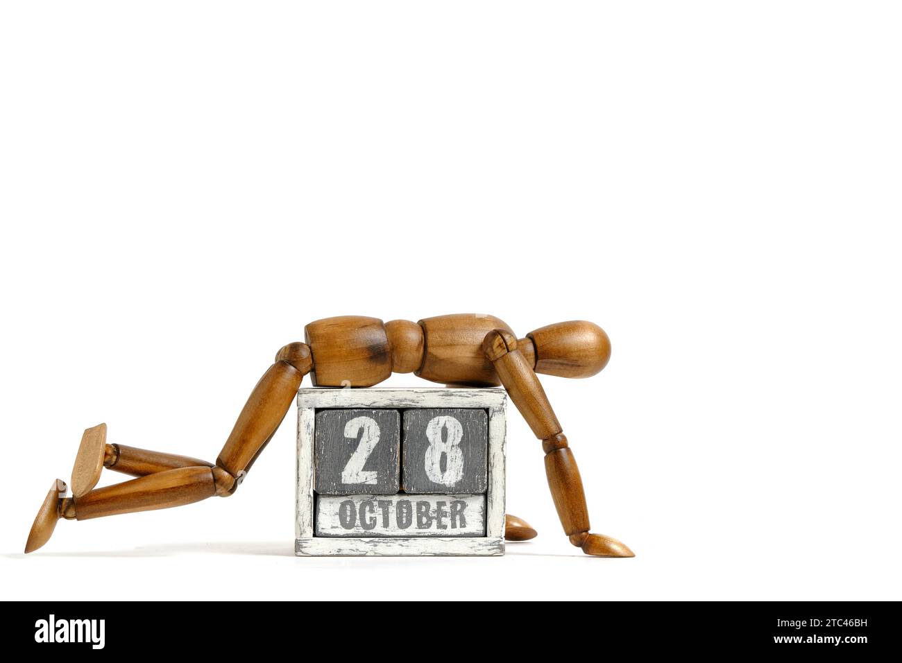 October 28, wooden calendar with mannequin lying on it on white ...