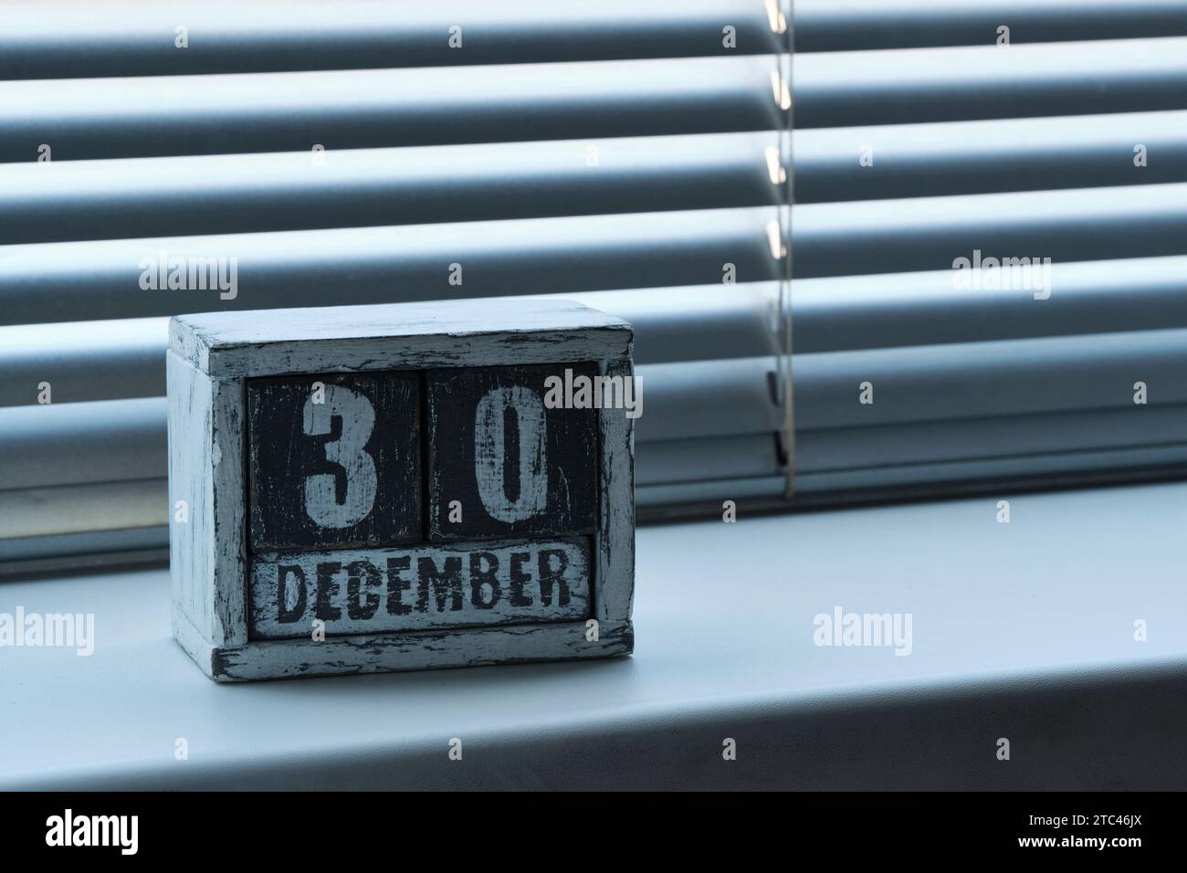 Morning December 30 on wooden calendar standing on window with blinds ...