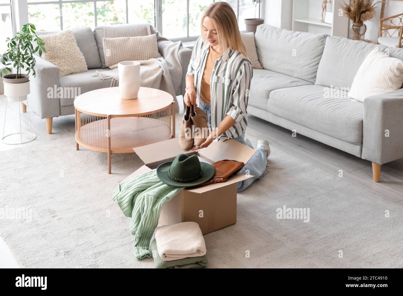 Young woman putting boots in box at home Stock Photo - Alamy
