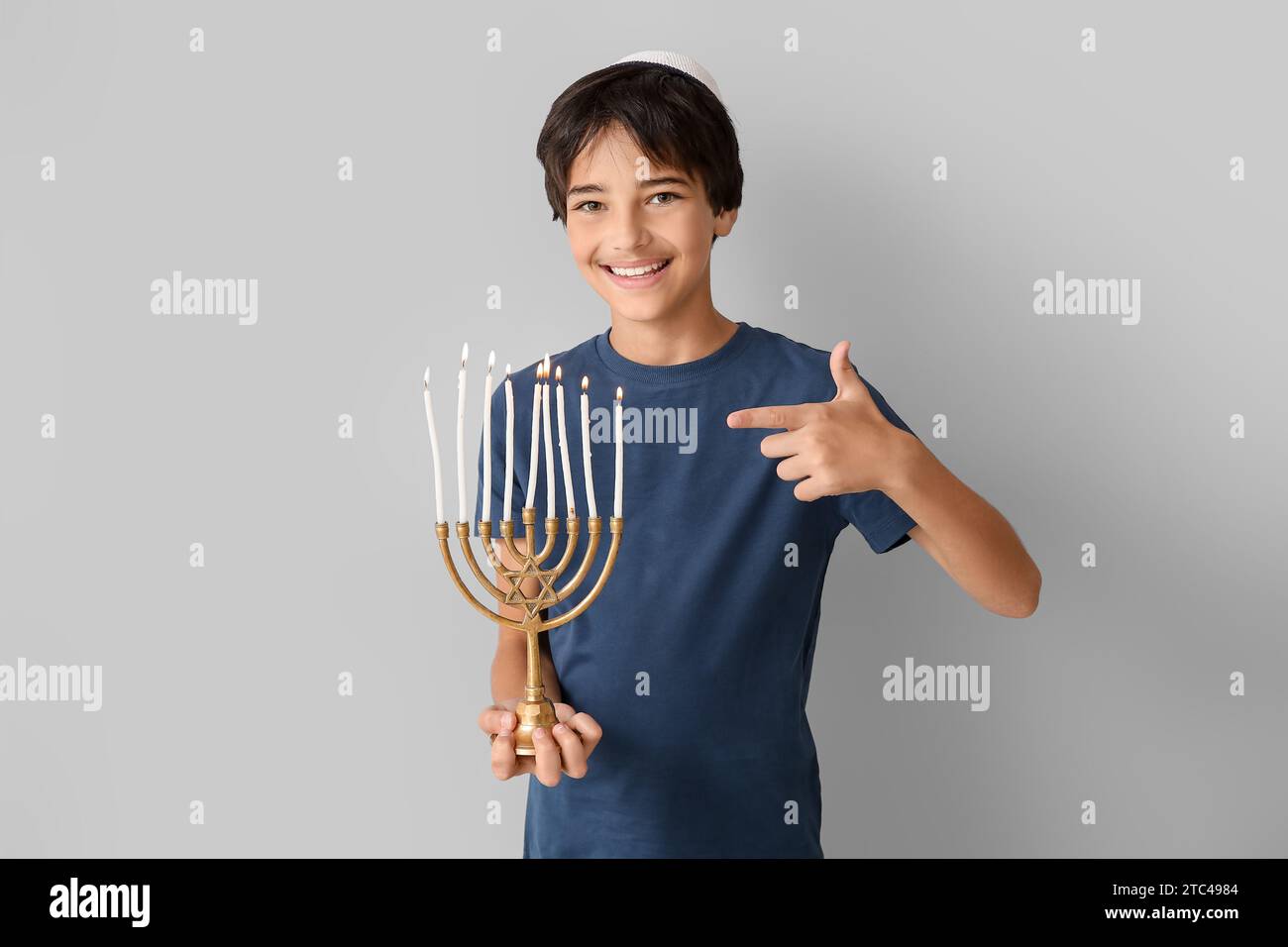 Little Israeli boy in kipa pointing at menorah on grey background Stock ...
