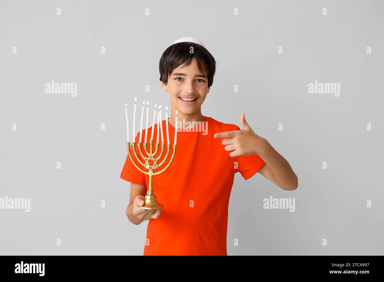 Little Israeli boy in kipa pointing at menorah on grey background Stock ...