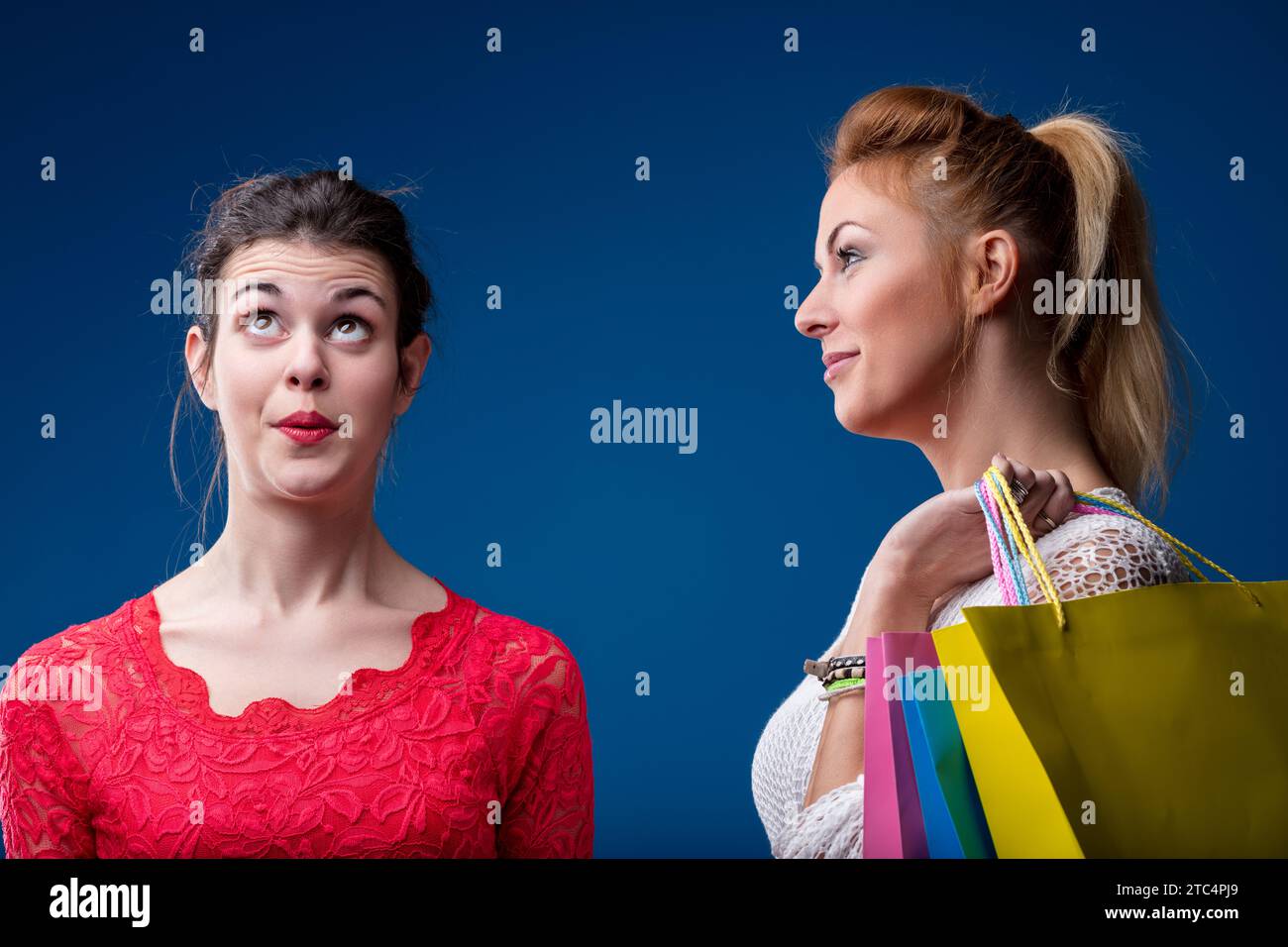 Two women share a moment; one with shopping bags looks back, the other ...