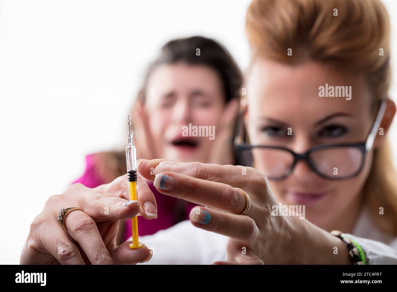 Medical professional carefully handles a needle, while a patient reacts ...