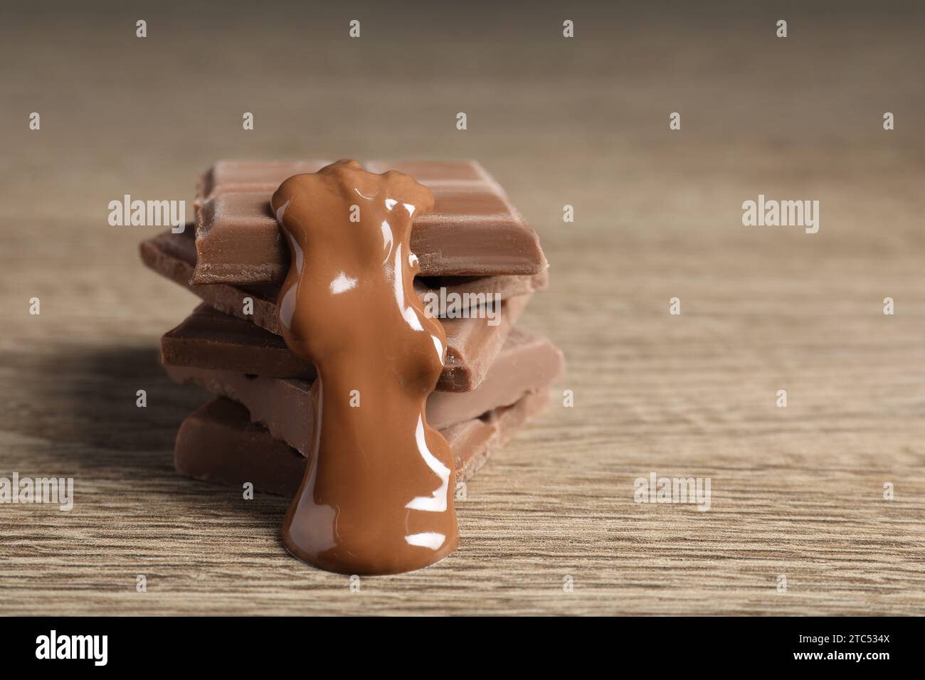 Pieces of milk chocolate with tasty paste on wooden table, closeup ...
