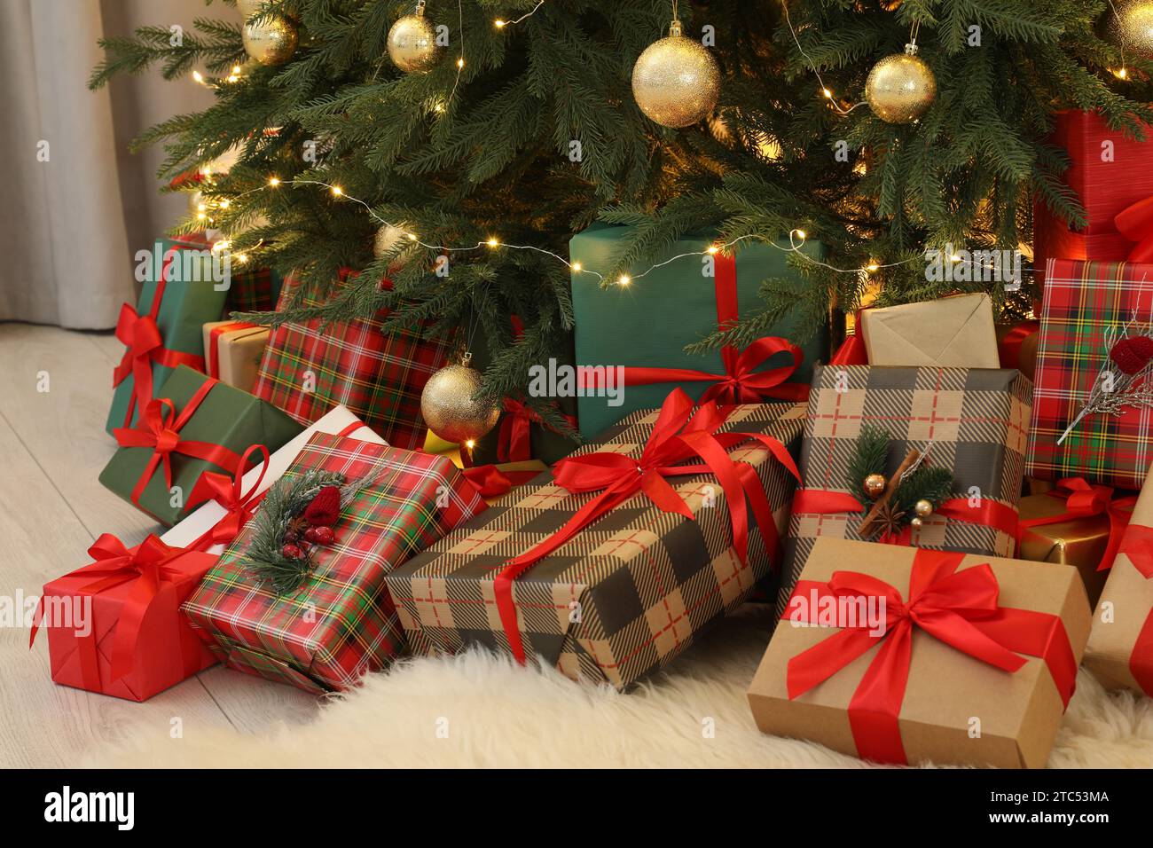 Many gift boxes under beautiful Christmas tree in room Stock Photo - Alamy