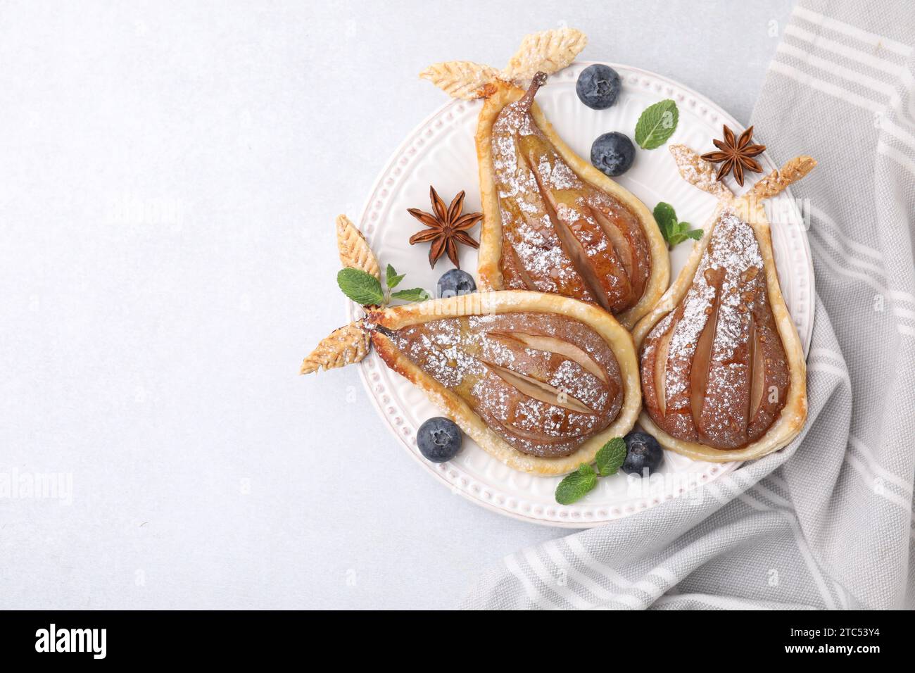 Delicious pears baked in puff pastry with powdered sugar on light table ...