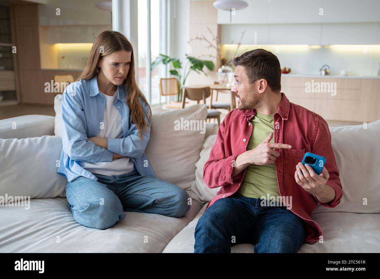 Annoyed wife listening explanations of cheater husband hiding phone ...