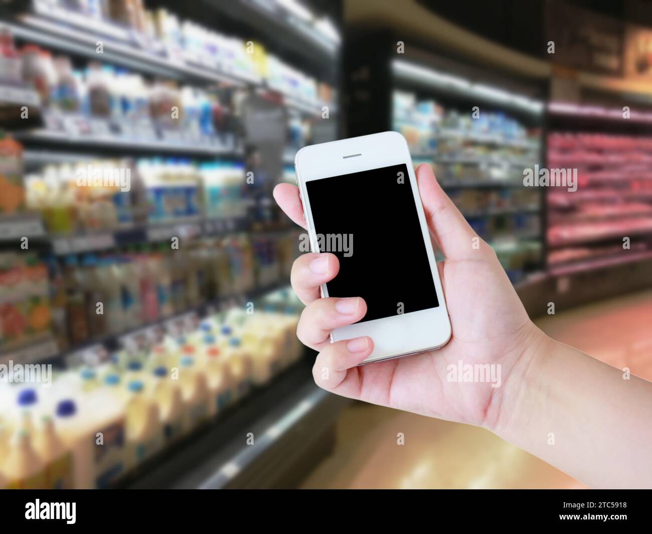 hand holding mobile phone with yogurts, soy milk and milk on the ...