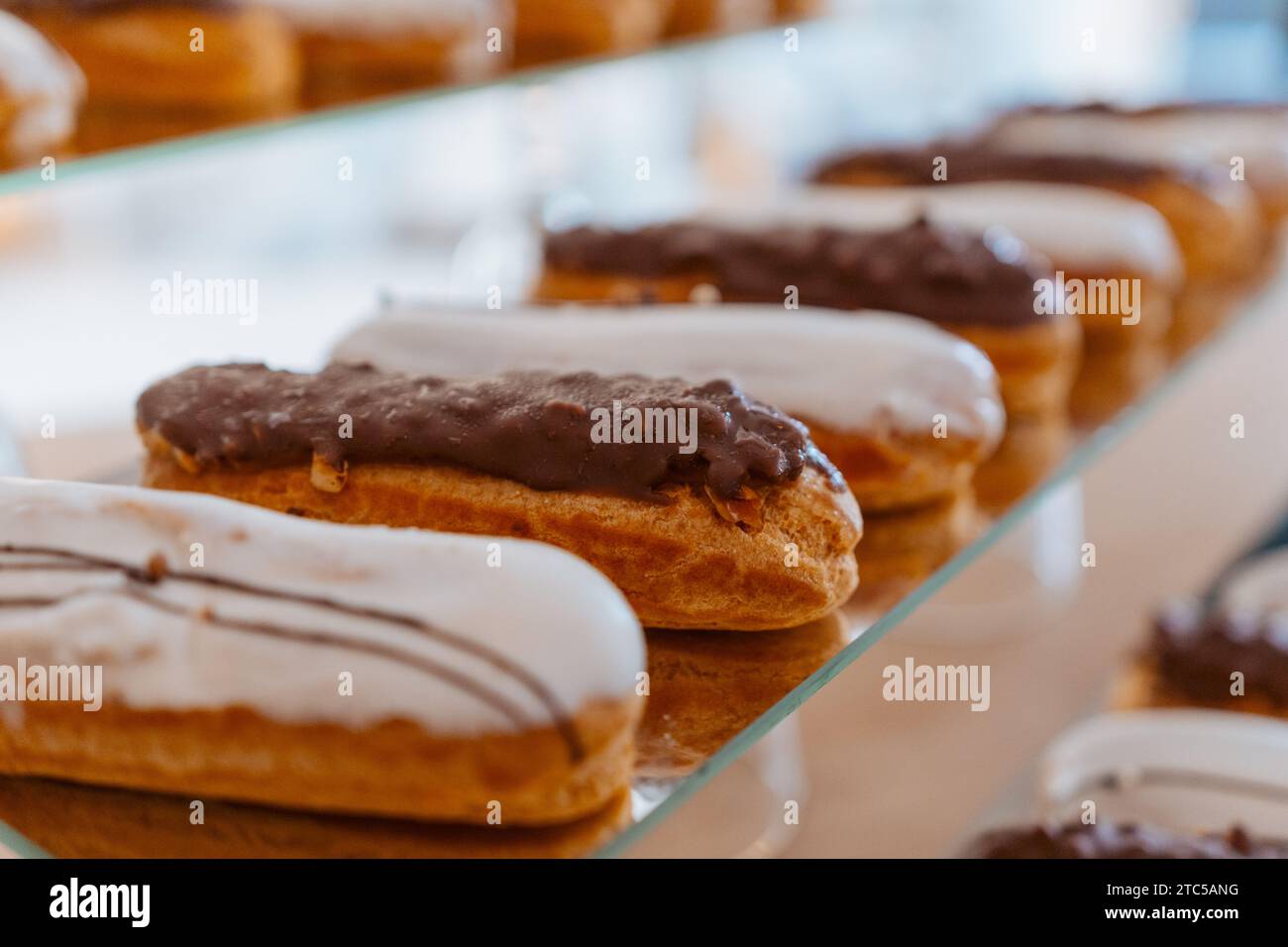 Eclairs with white and chocolate icing are laid out in a row on a ...