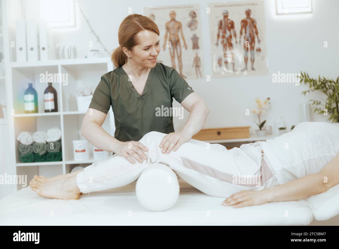 Healthcare time. happy female massage therapist in massage cabinet with client conducting ...