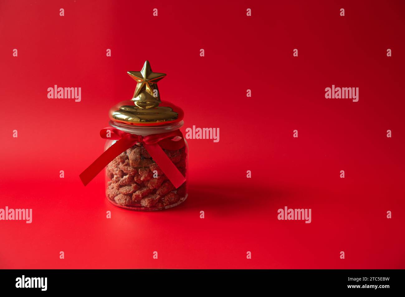 Glass container with Christmas star filled with sweets on red ...
