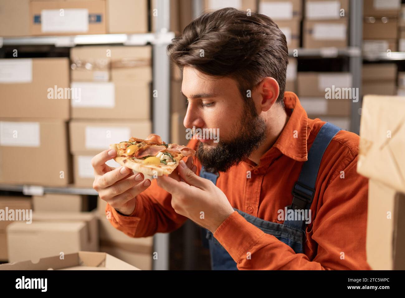 Warehouse worker having meat pizza from fast food delivery for lunch ...