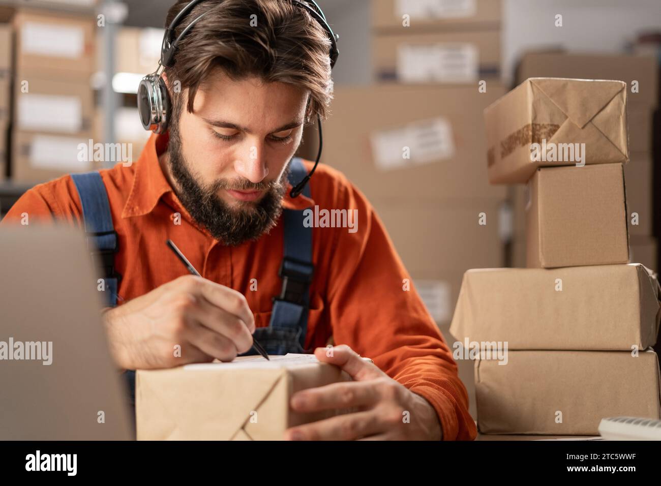 Caucasian male warehouse operator delivering goods takes an order using ...