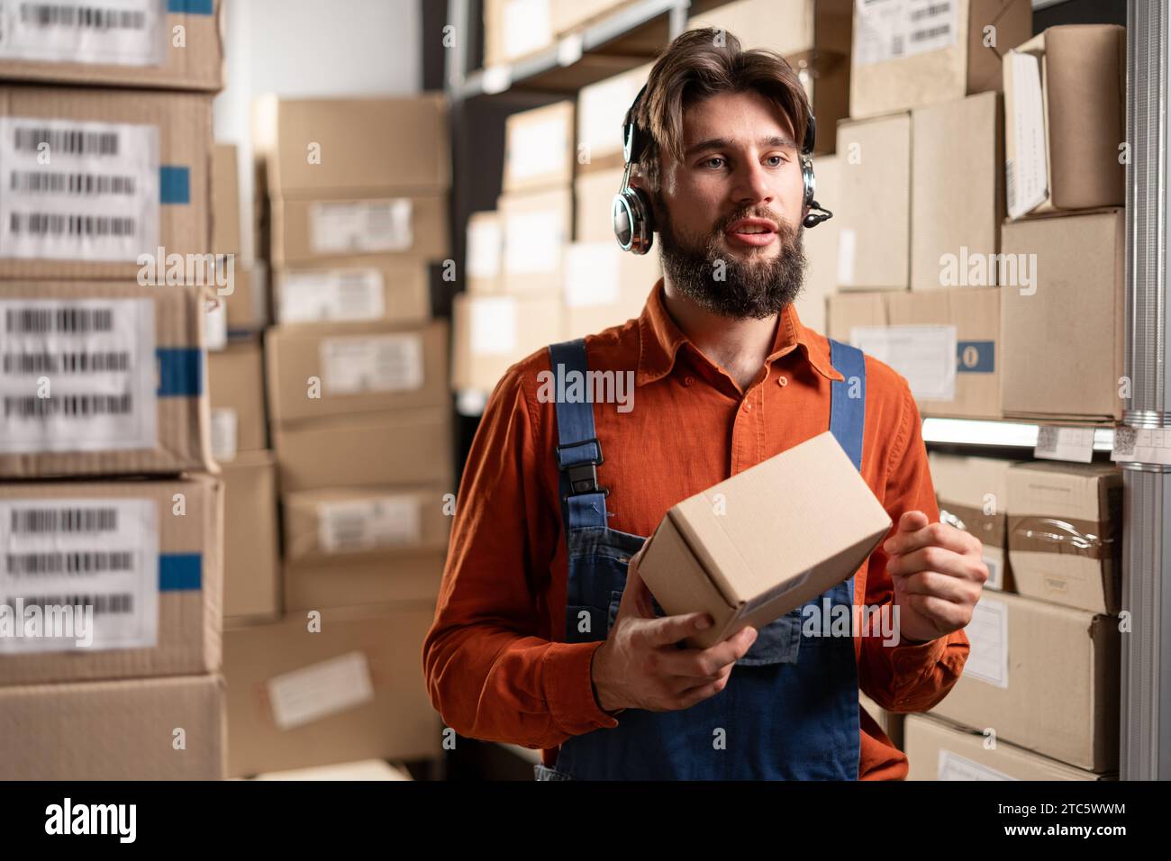 Caucasian male warehouse operator delivering goods dressed in blue ...