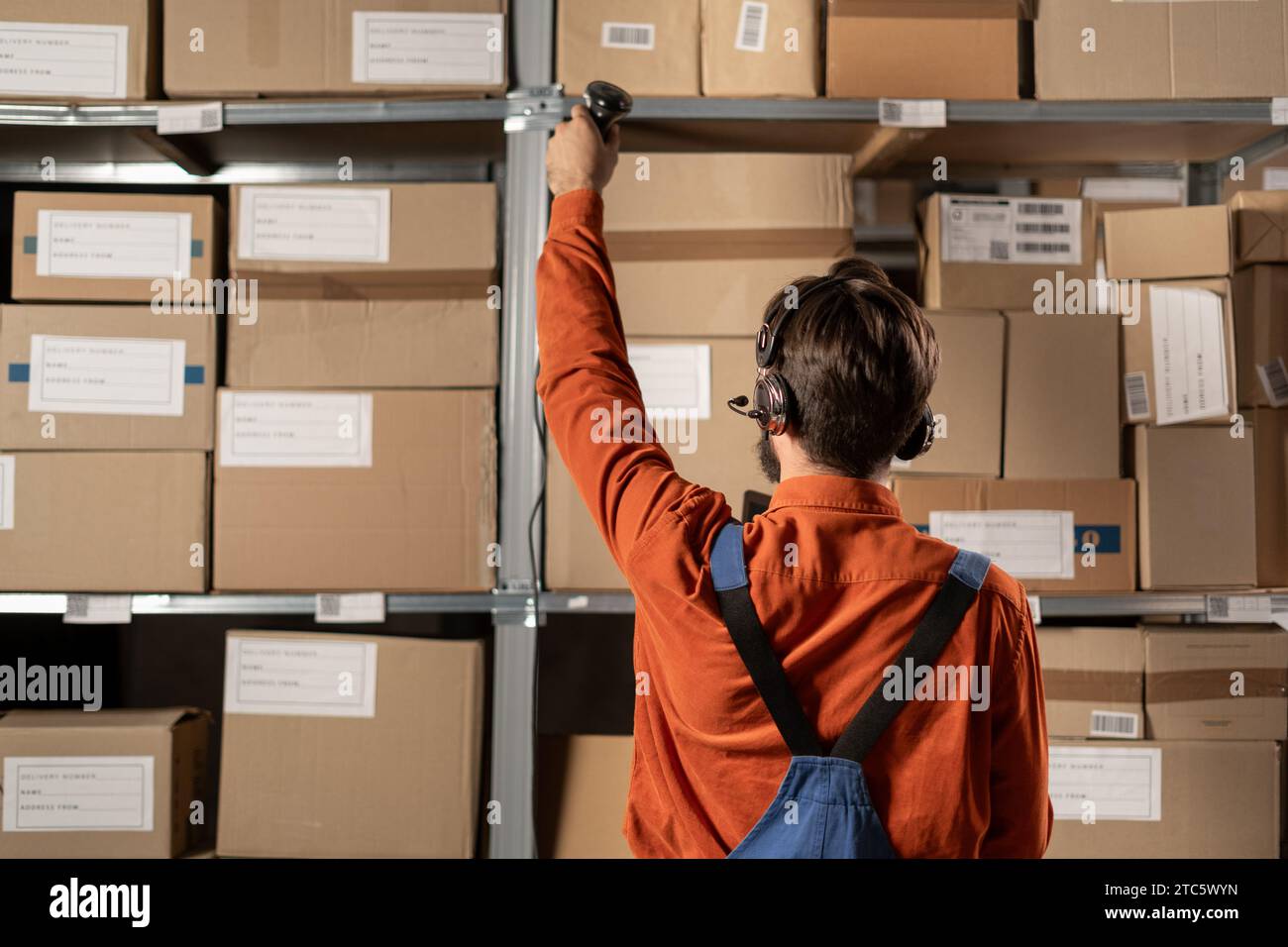 Caucasian male warehouse operator delivering goods, dressed in blue ...