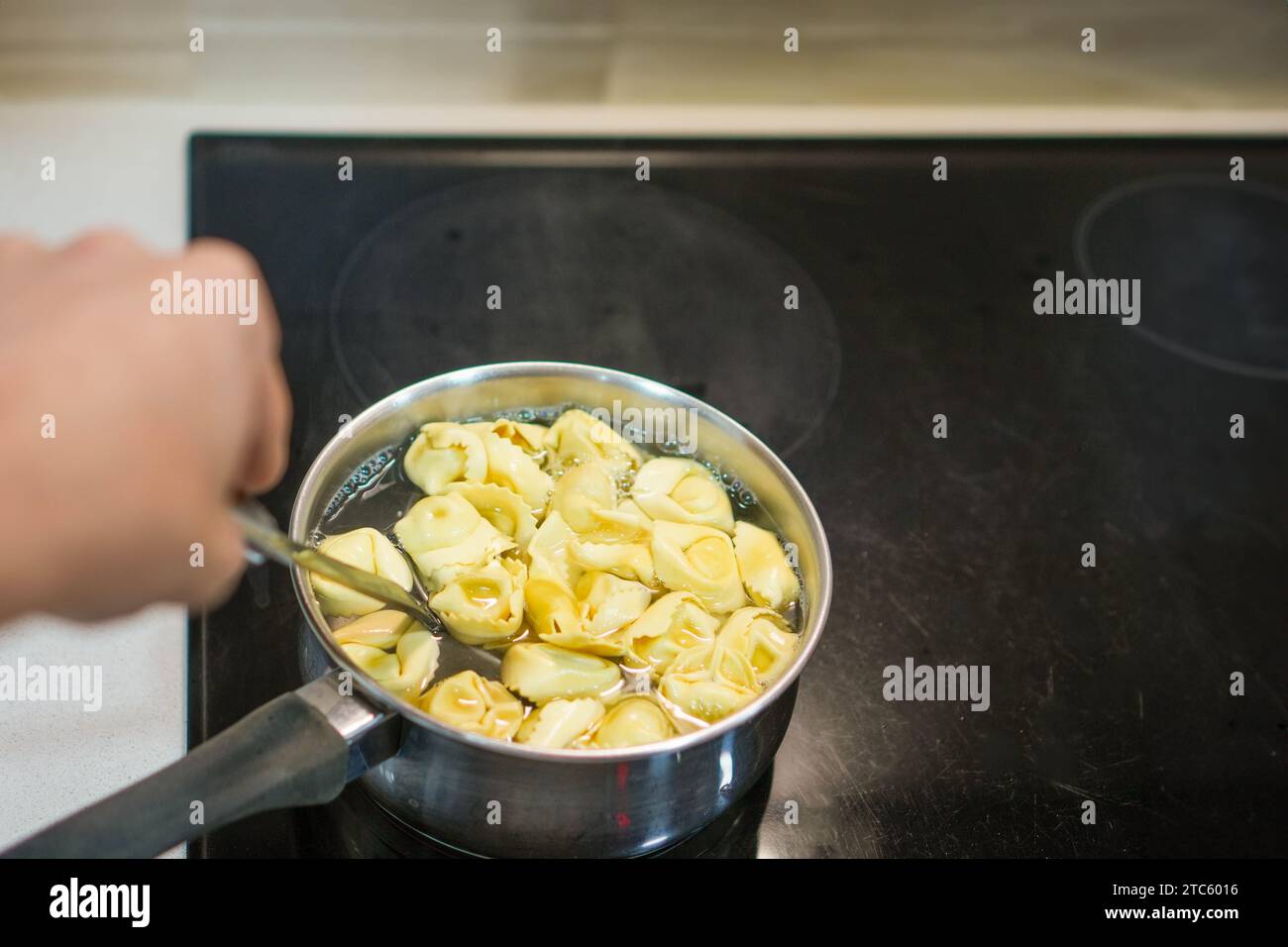 Ravioli with cottage cheese and spinach boiling in water inside a metal ...