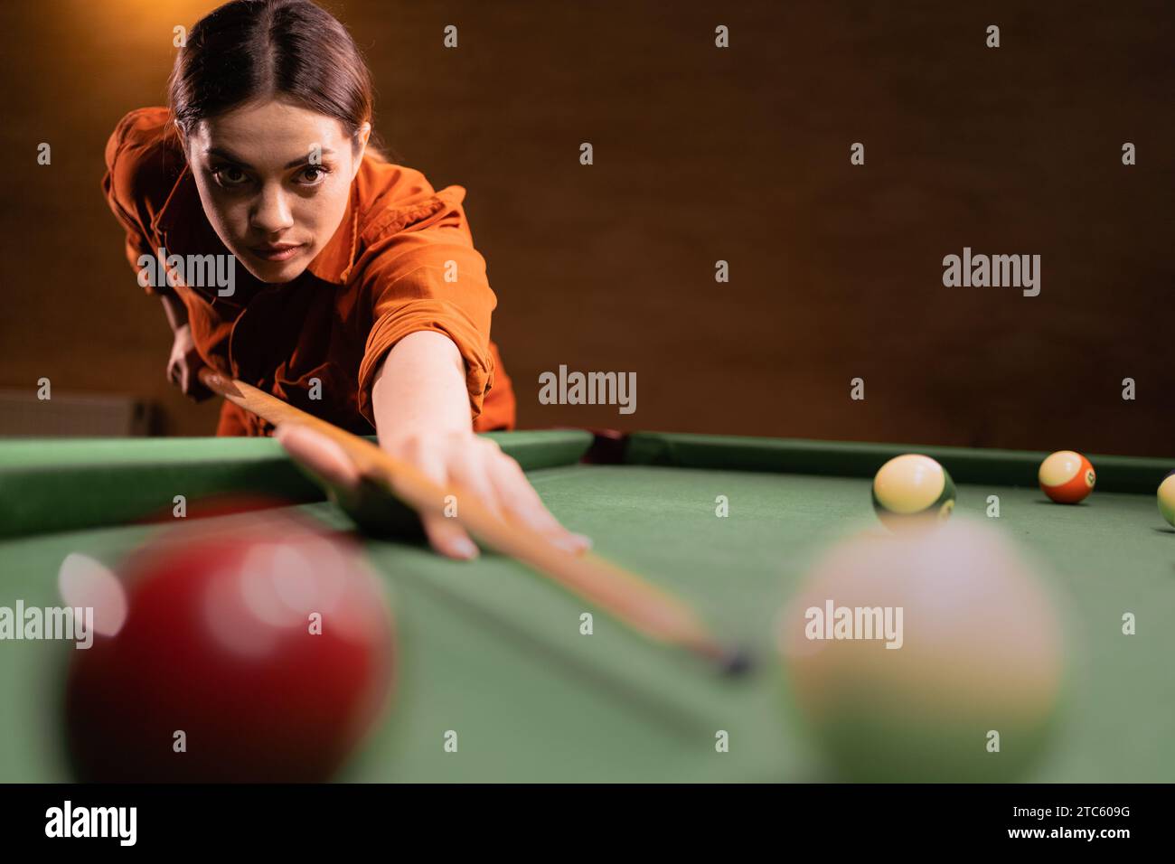 Female billiard player using the cue stick while playing billiard at ...