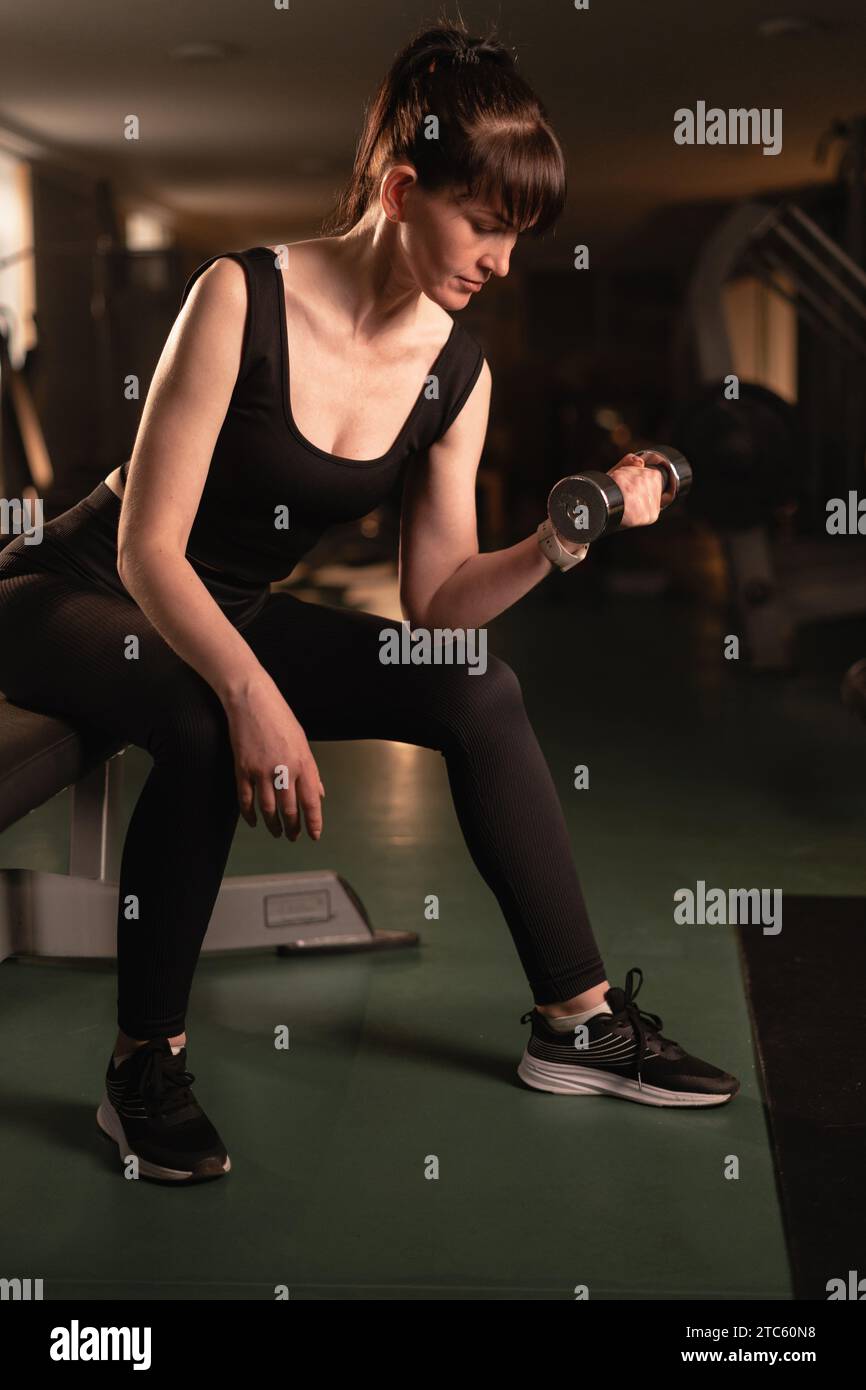 Beautiful slim woman wearing leggings doing biceps workouts with ...