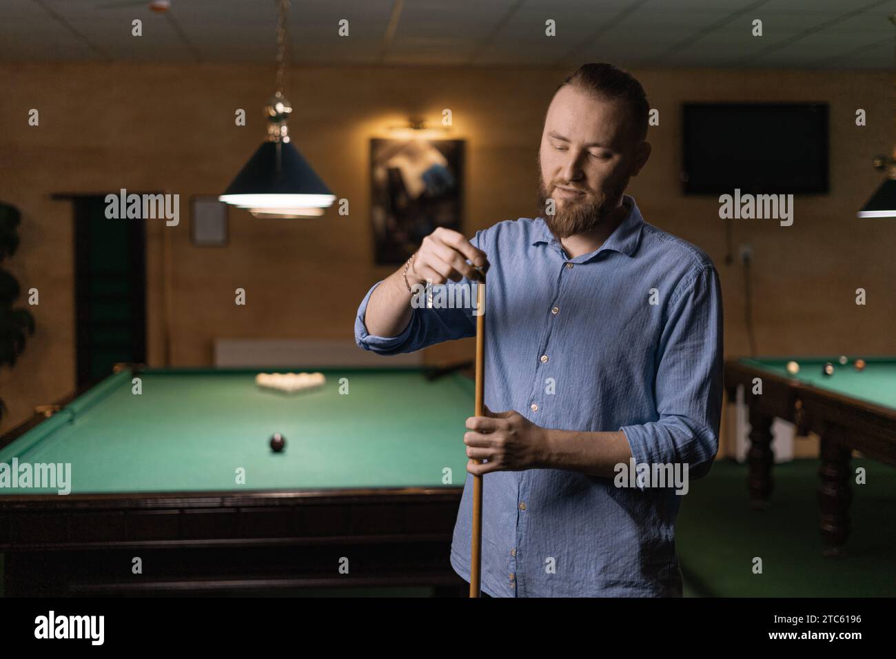 Male snooker player prepares to play billiards by rubbing his cue with ...