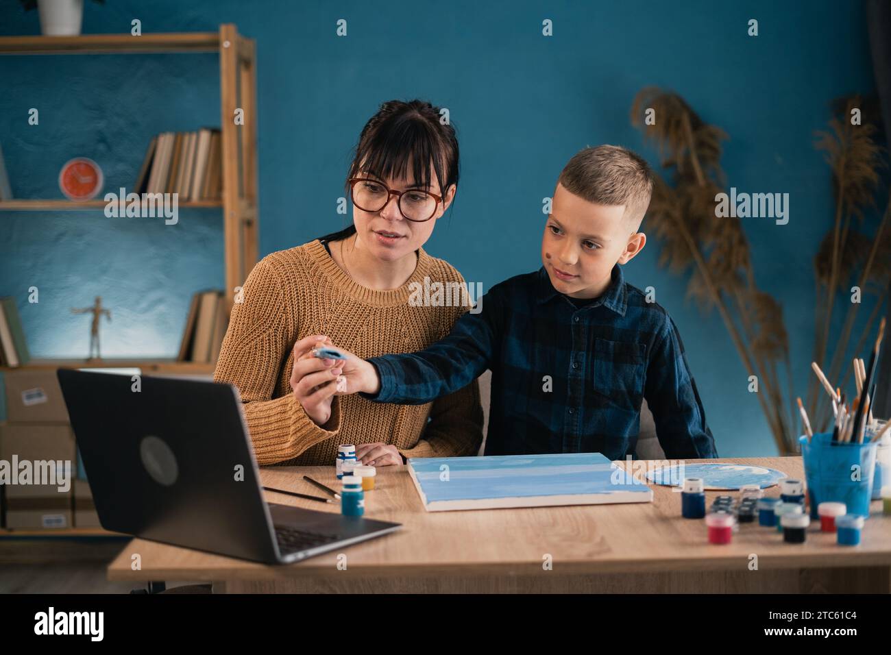 Cute boy taking online art class with mother helping him. Child and ...