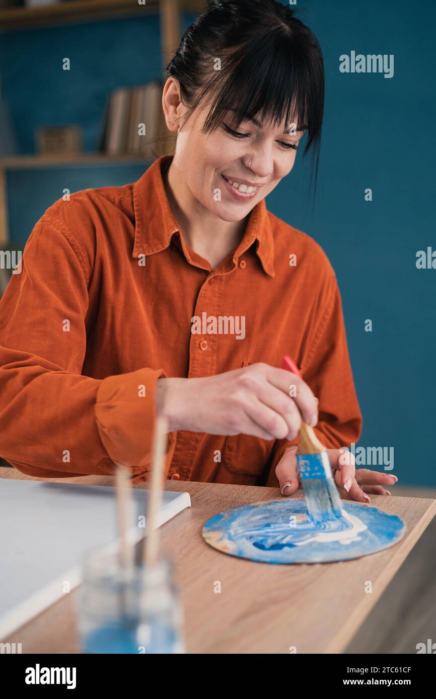 Happy woman with canvas and paints painting at home. Portrait of young ...