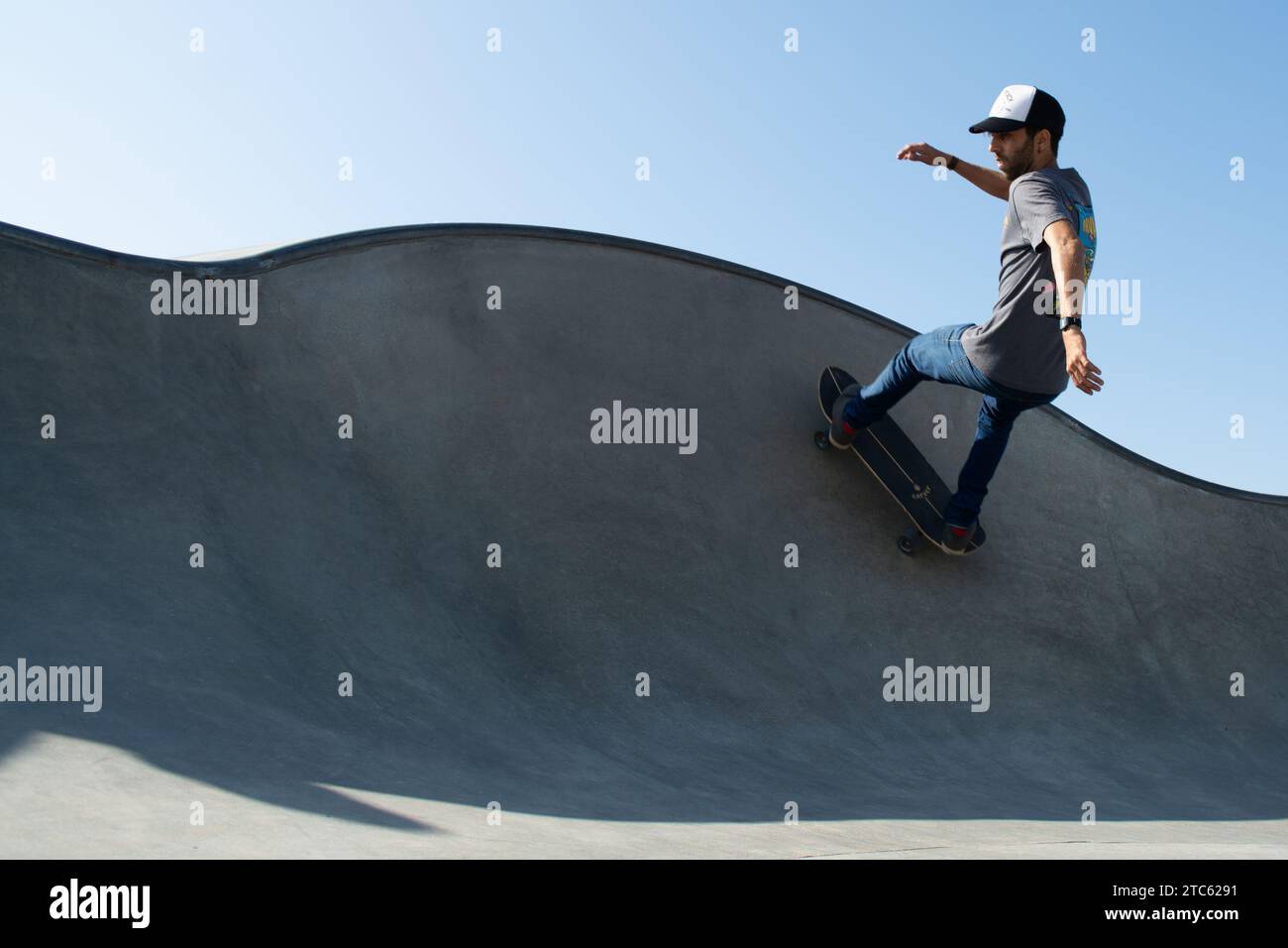 A young male performing skateboarding at an outdoor skateboard park ...