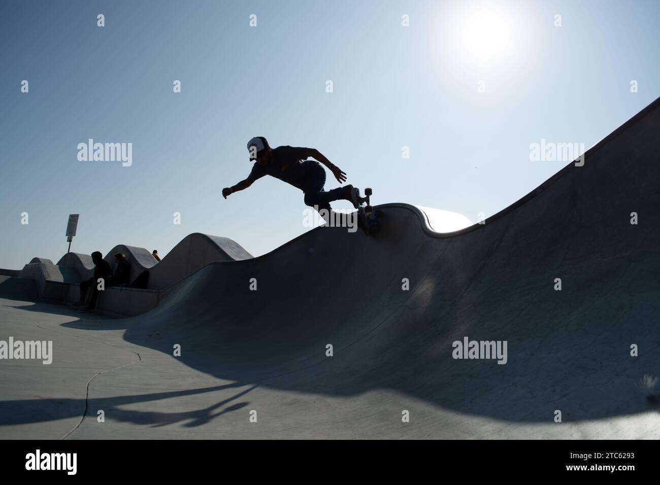 A young male performing skateboarding at an outdoor skateboard park ...